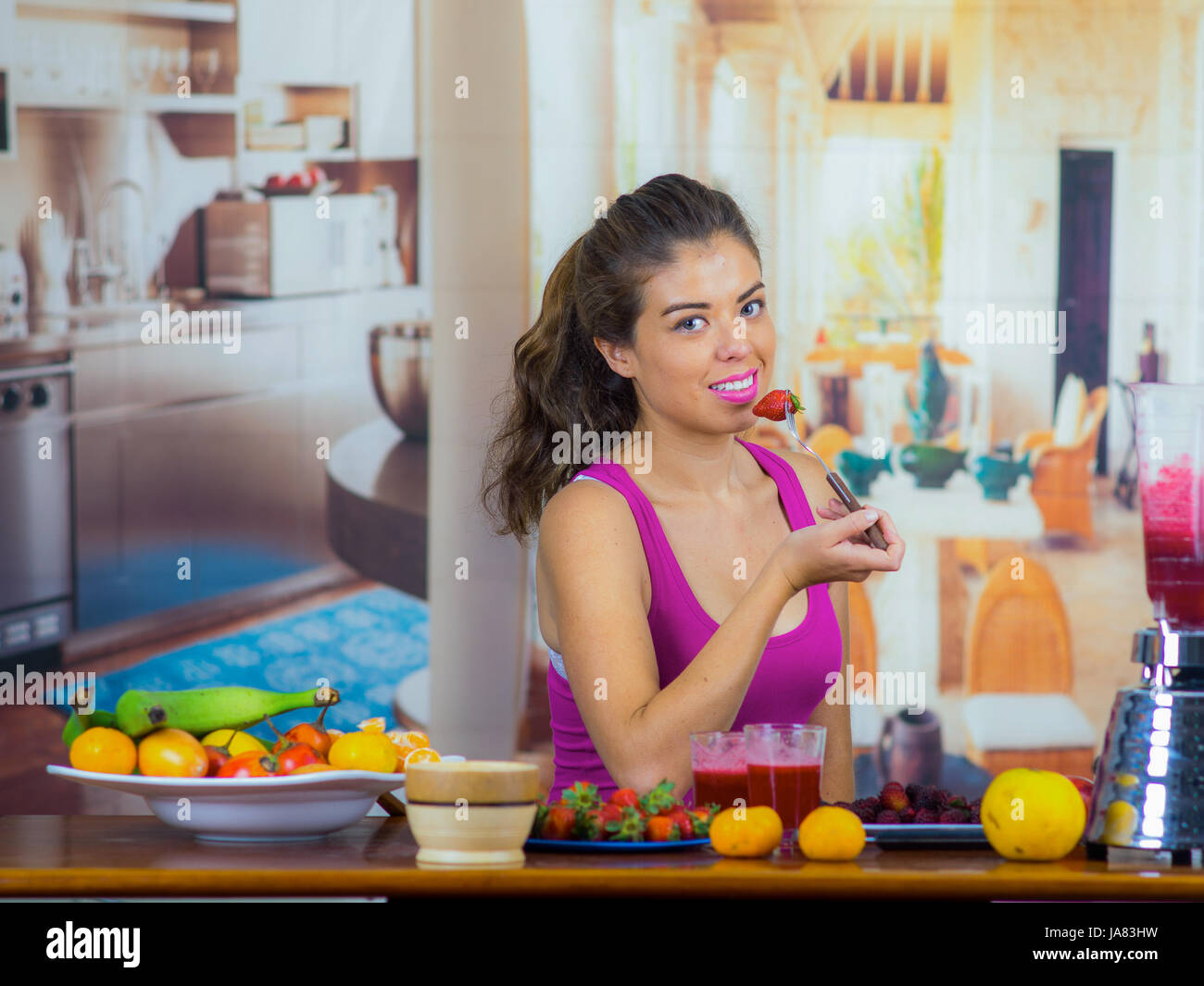 Young woman wearing pink top enjoying healthy breakfast, eating fruits ...