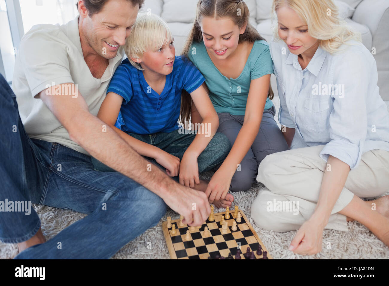 Portrait of a cheerful family playing chess lying on a carpet Stock ...