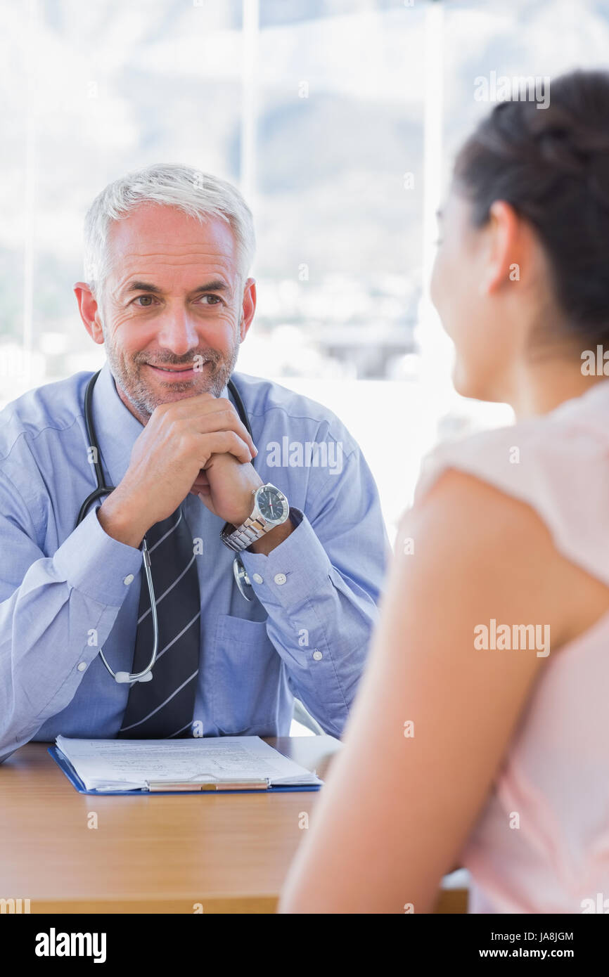 Smiling doctor listening to patient in his office Stock Photo - Alamy