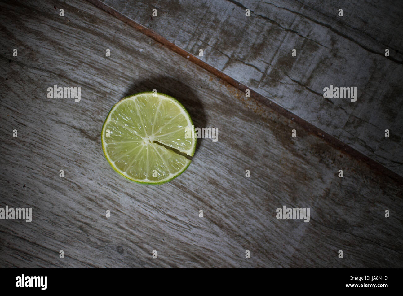 A wedge of lime on a wooden table Stock Photo - Alamy