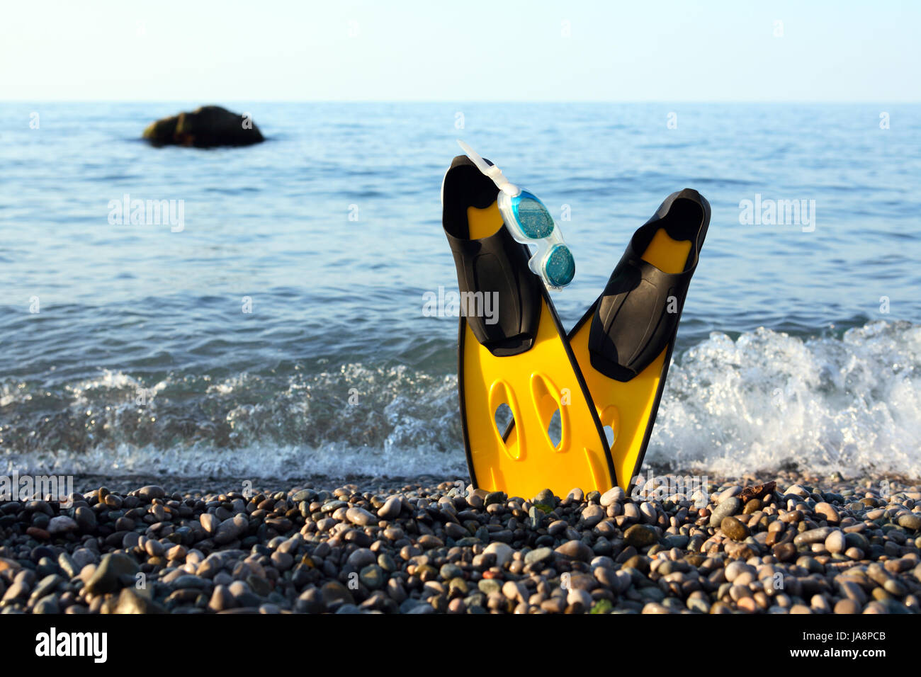 Diving concept. Pair of yellow flippers and goggles on seashore with ...