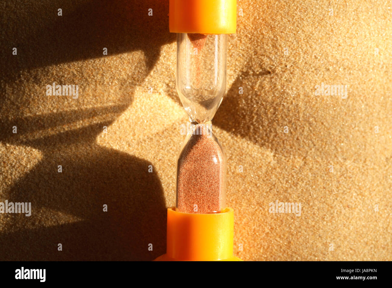 Time concept. Closeup of hourglass on abstract sand background with ...