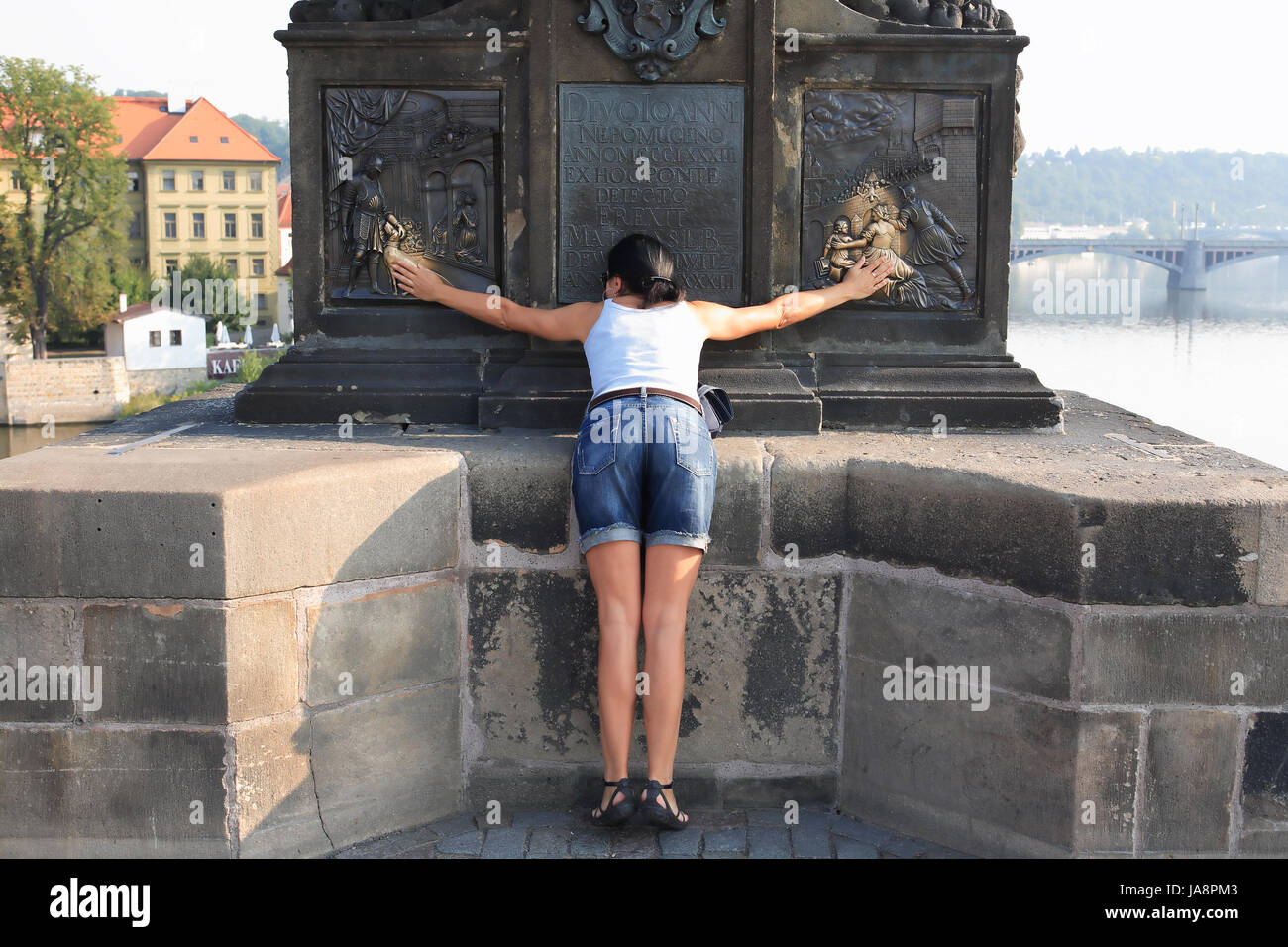 Woman touching ancient sculpture for her wishes. Charles Bridge, Prague ...