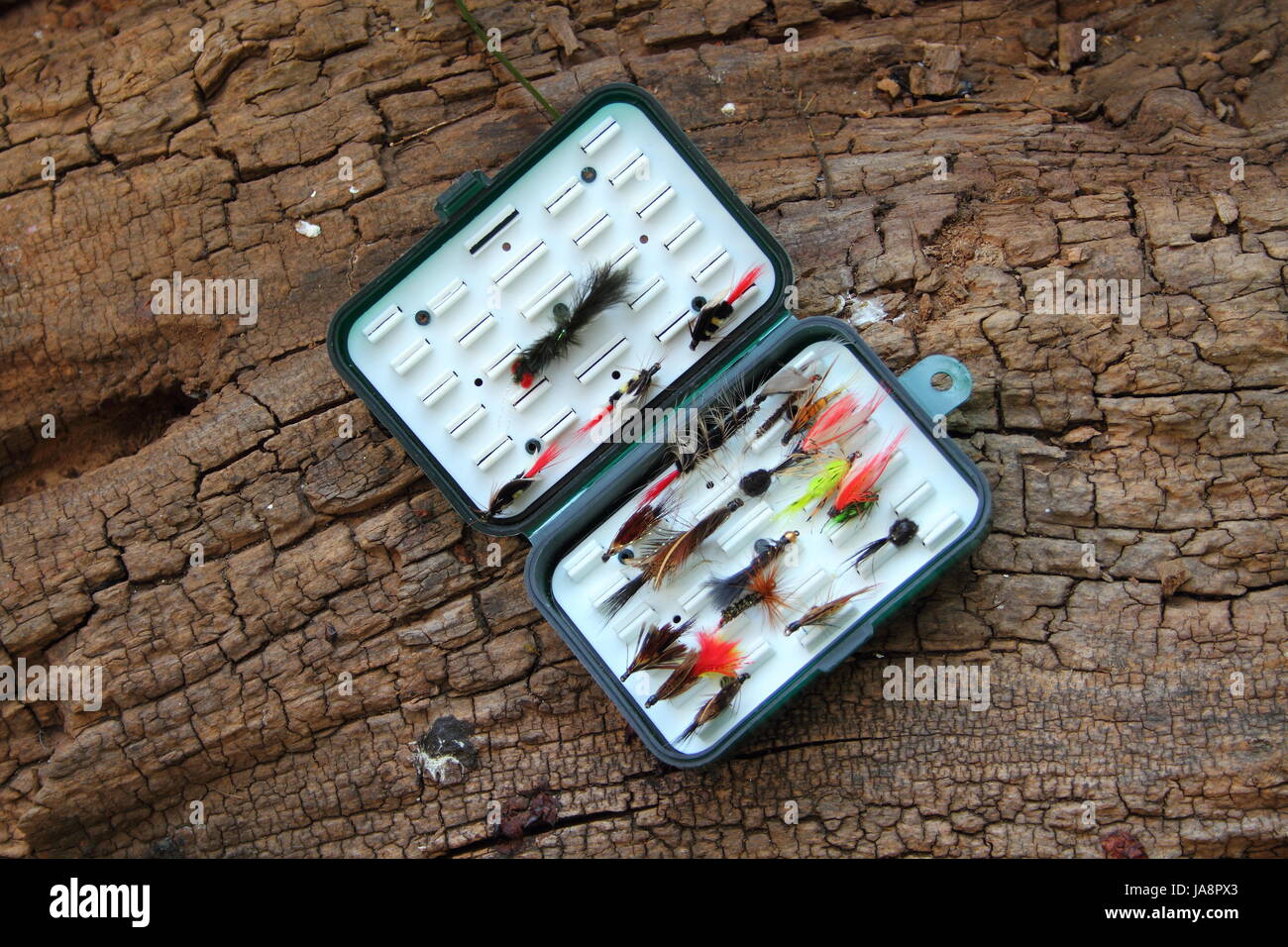Artificial fly fishing flies outdoors on a log Stock Photo - Alamy
