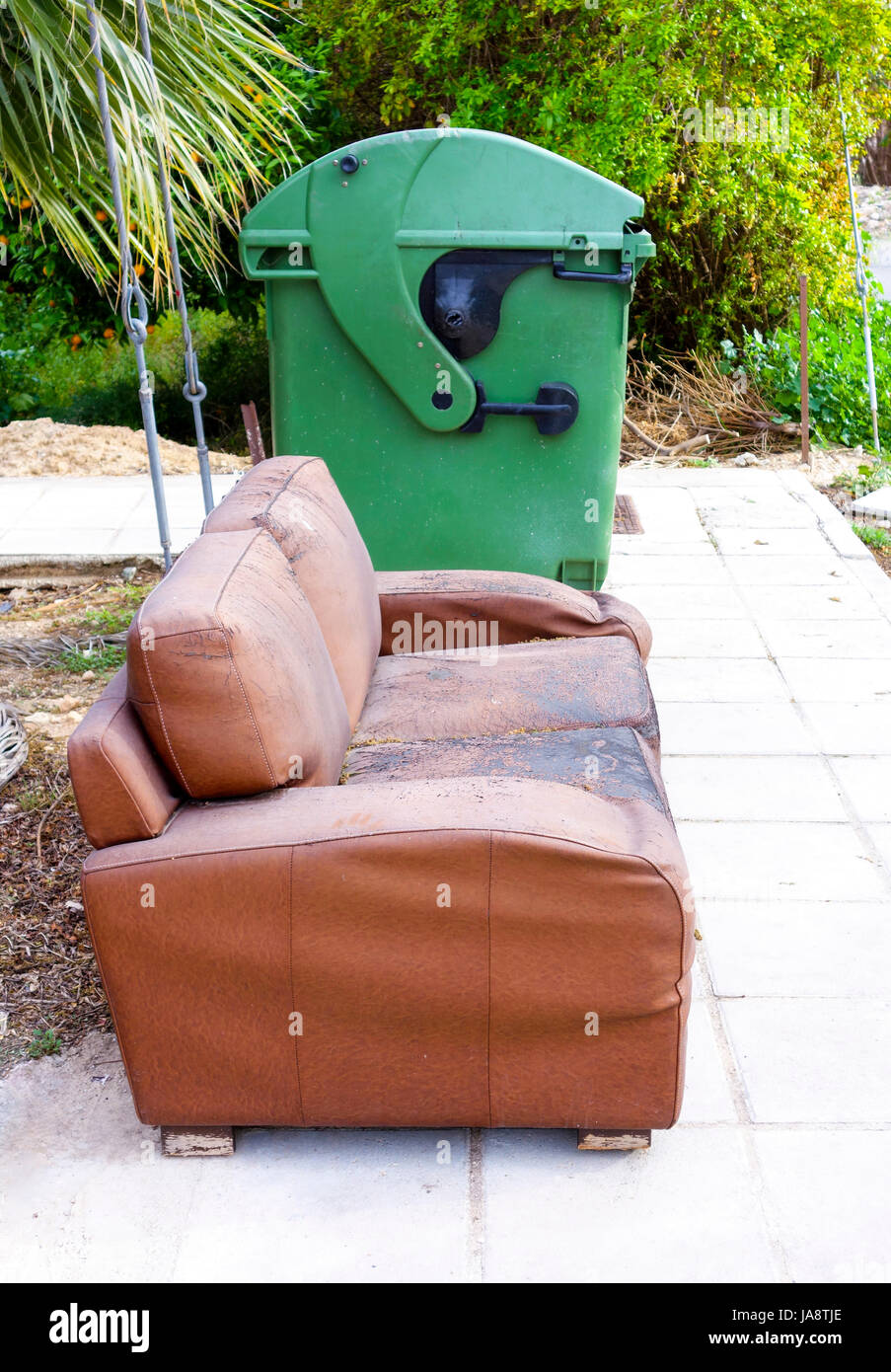Old sofa near green trash can in the street Stock Photo - Alamy