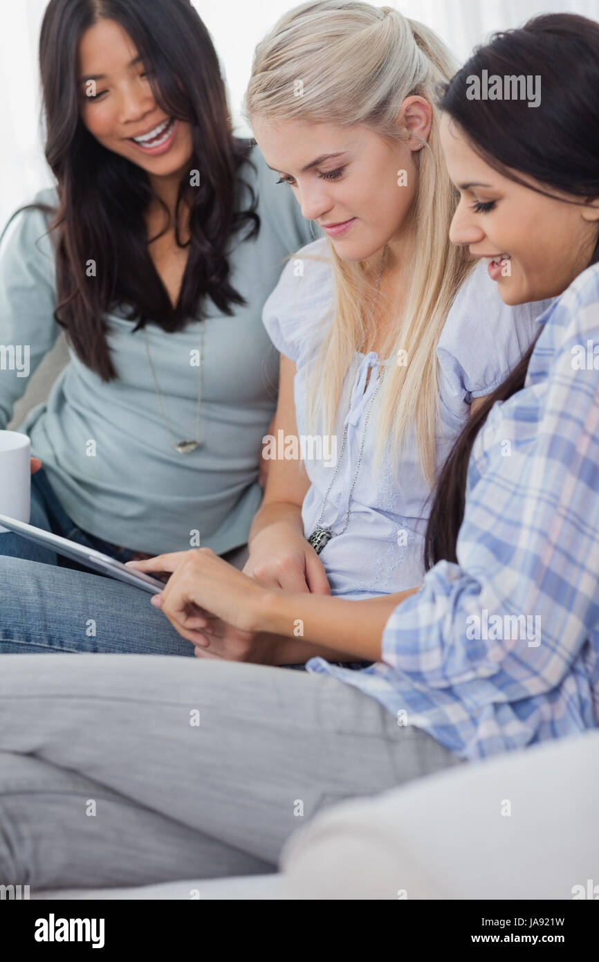 Happy friends using digital tablet together at home on couch Stock ...