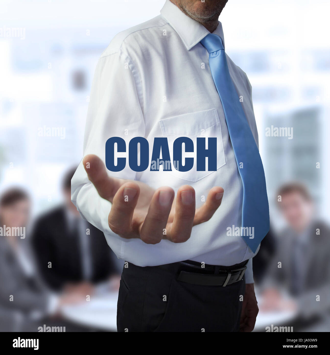 Smart businessman holding the word coach in front of a business team ...