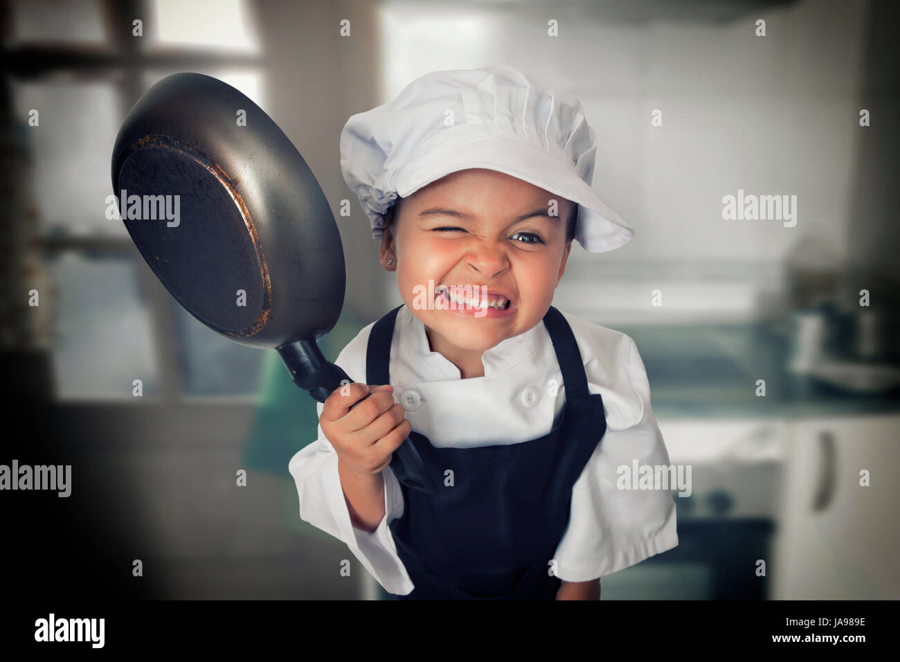Portrait of a funny four years girl cooking in the kitchen with angry ...