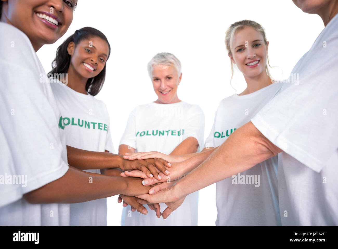 Group of female volunteers with hands together smiling at camera on ...
