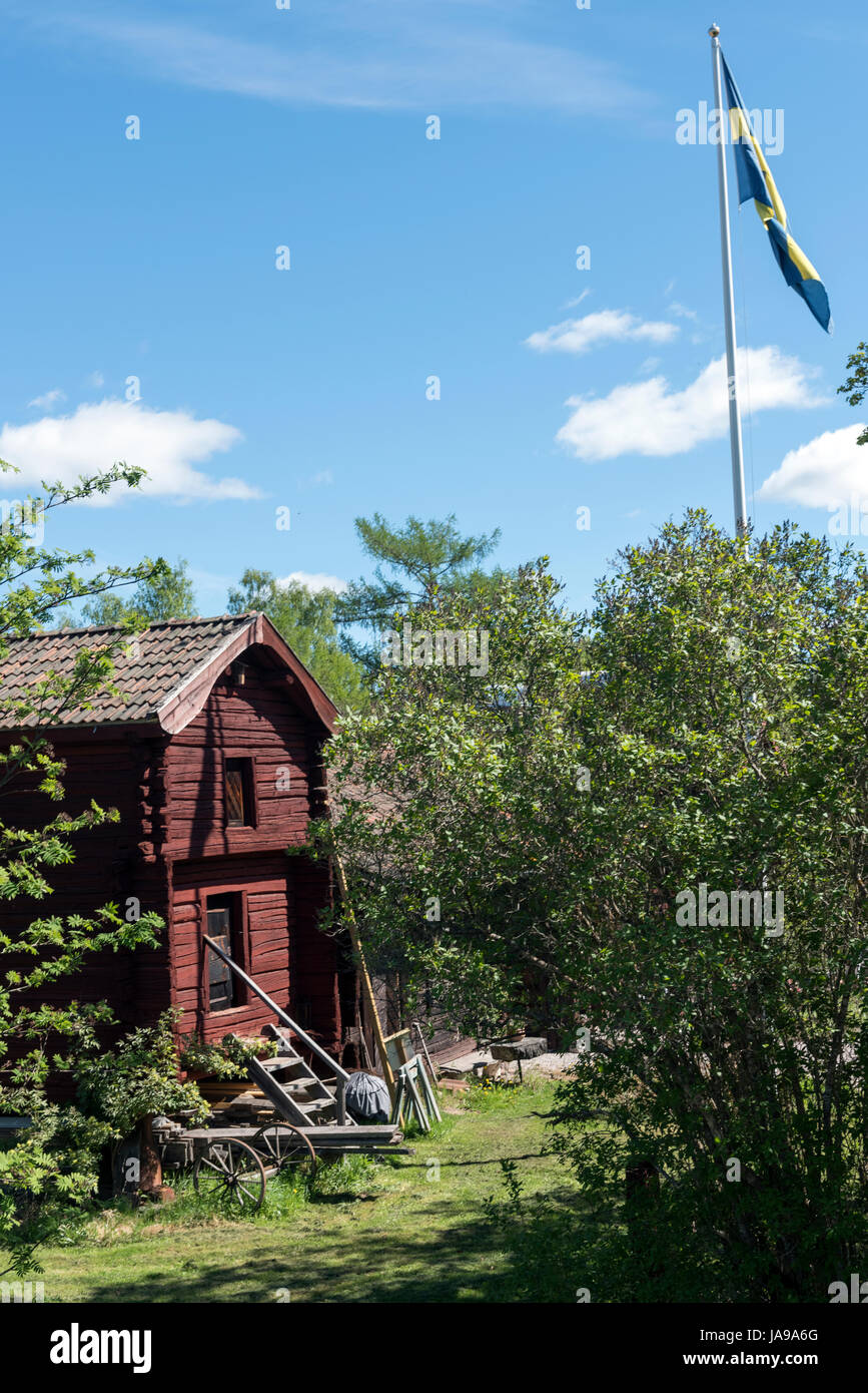Traditional red wooden Swedish house with national flag flying on a ...