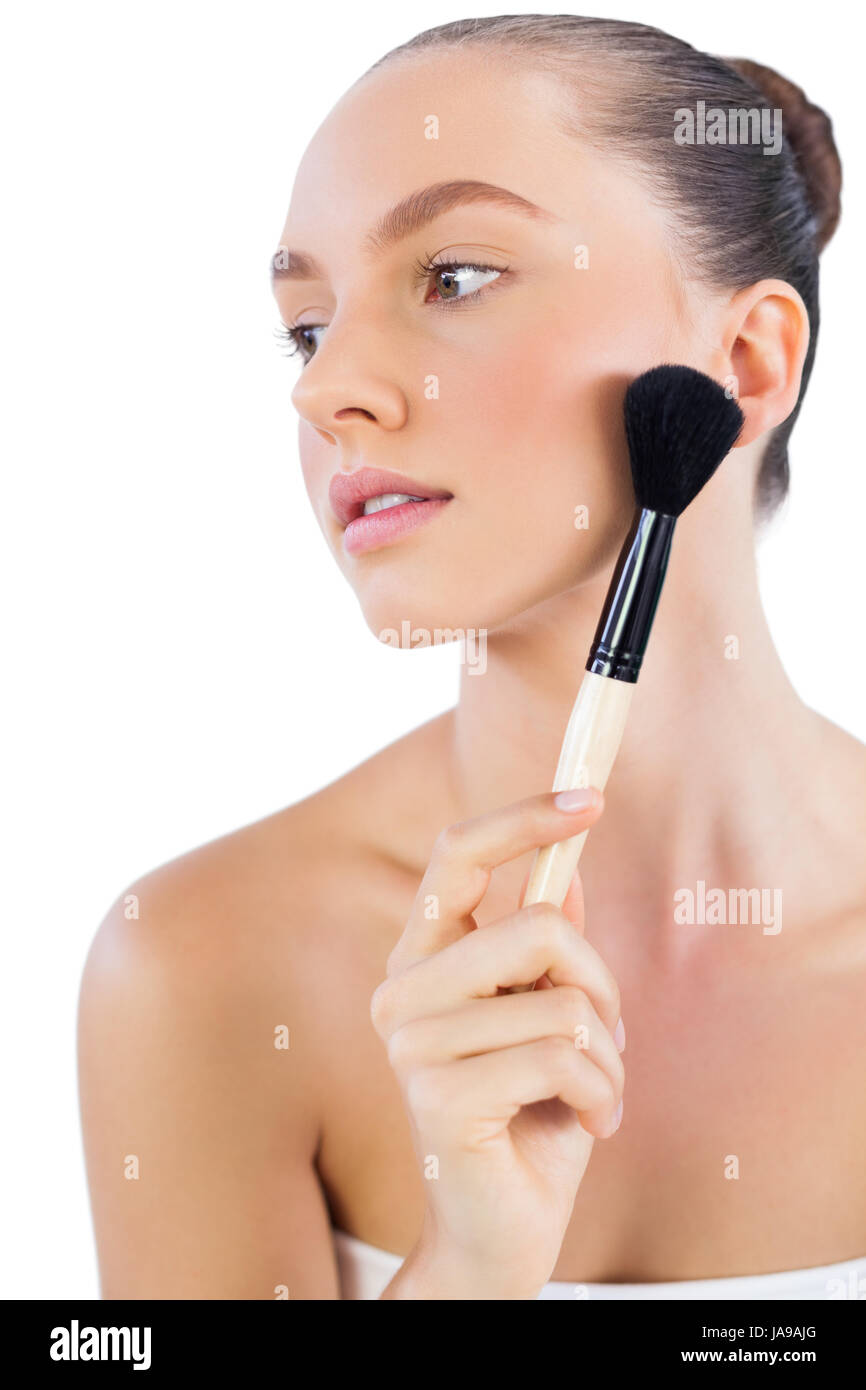 Model touching her face with powder brush and looking away Stock Photo ...