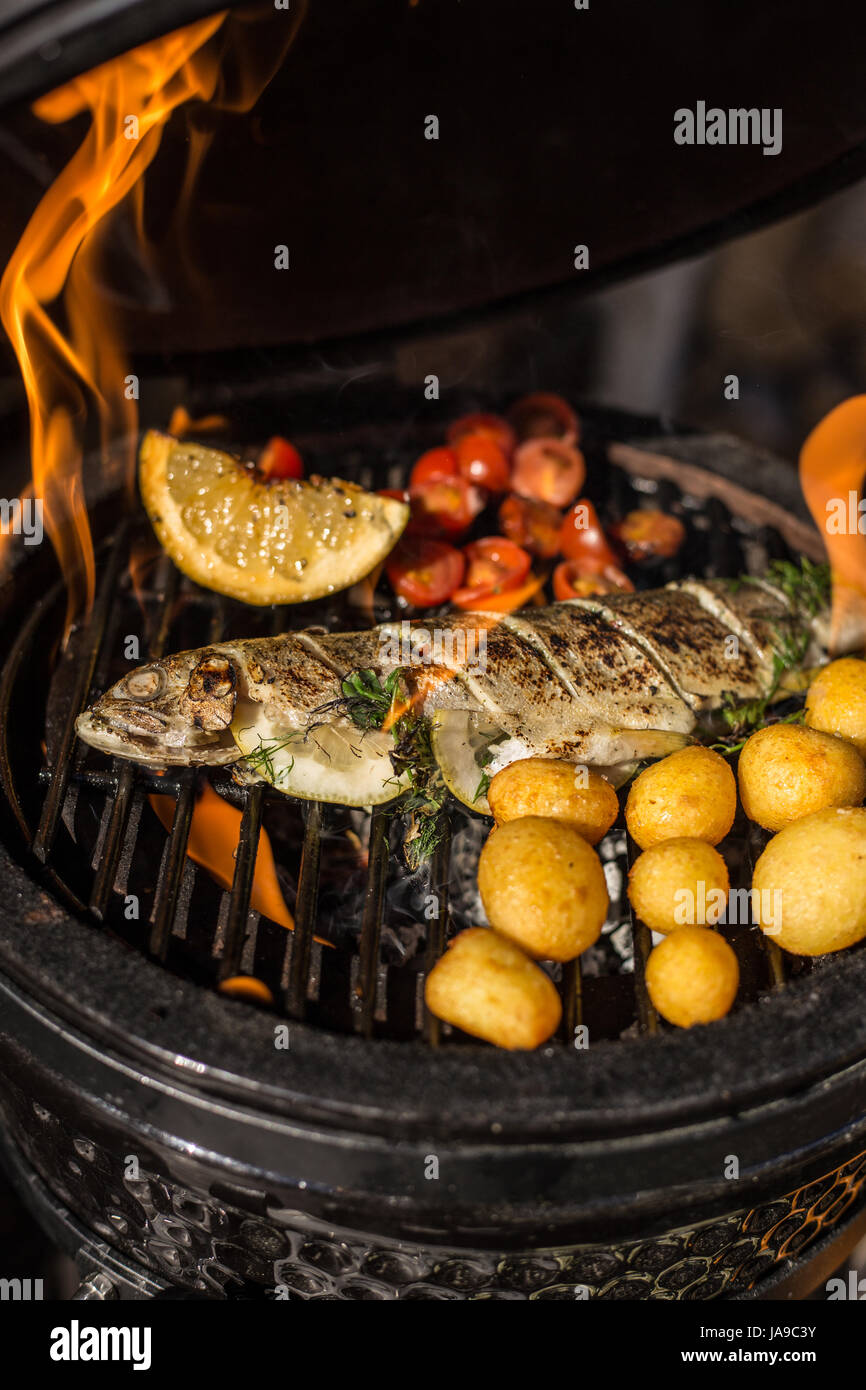 Delicious rainbow trout fish with tomatoes, potatoes and lemon cooking ...