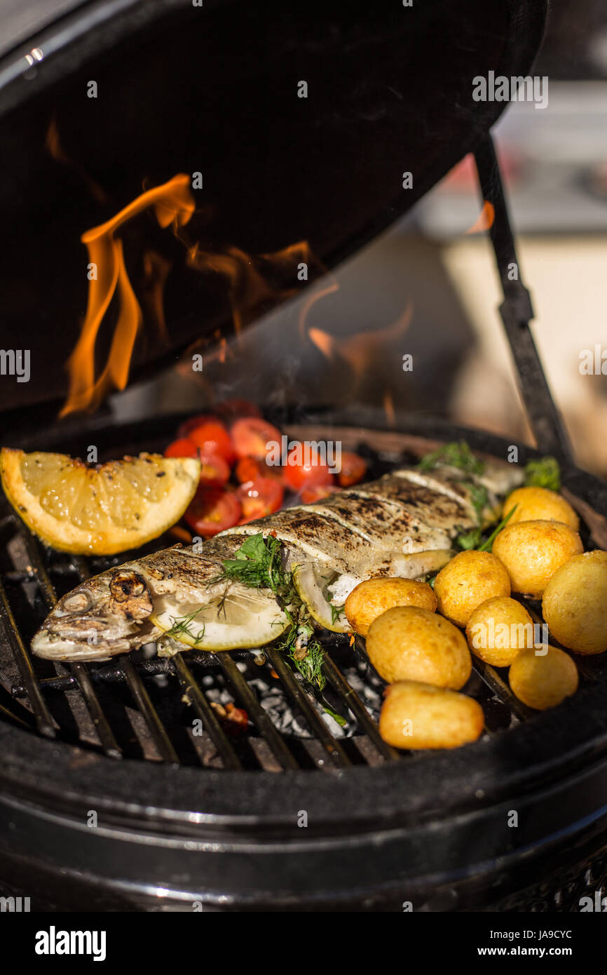 Delicious rainbow trout fish with tomatoes, potatoes and lemon cooking ...