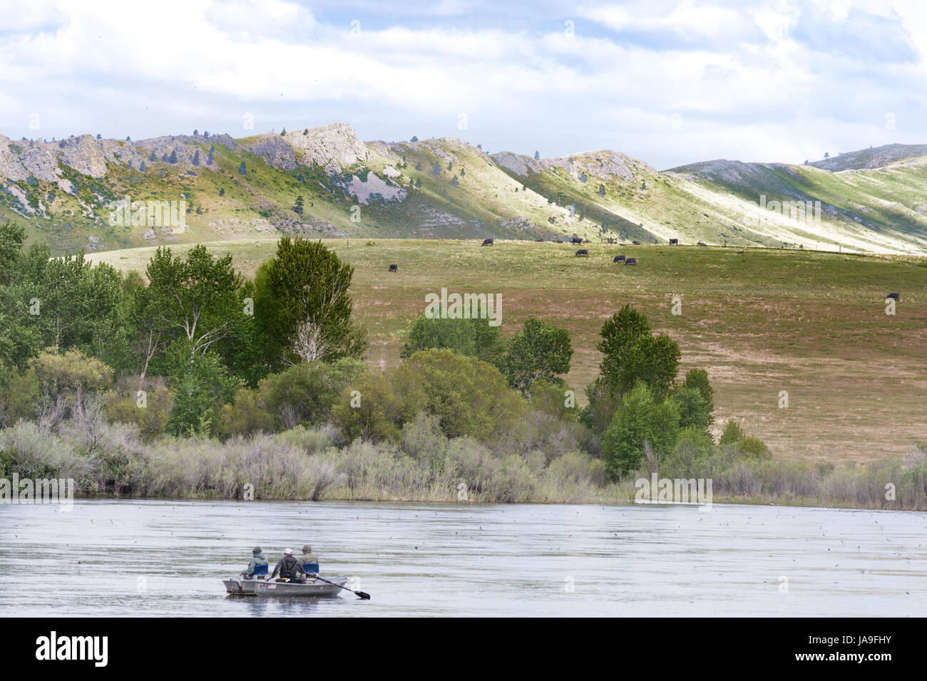 Two men fishing and a third man rowing in the Missouri River with backs ...