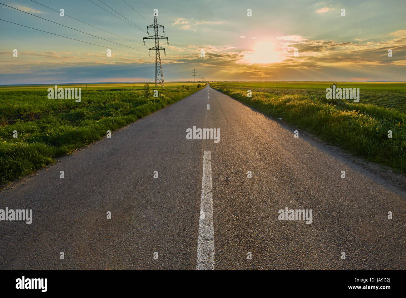 Empty road at sunset through wheat fields Stock Photo - Alamy