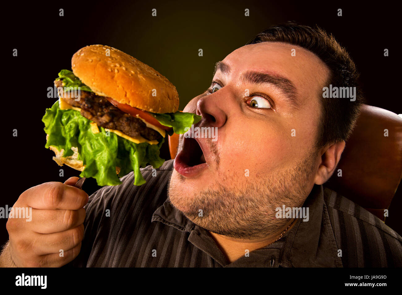 Fat man eating fast food hamberger. Breakfast for overweight person ...