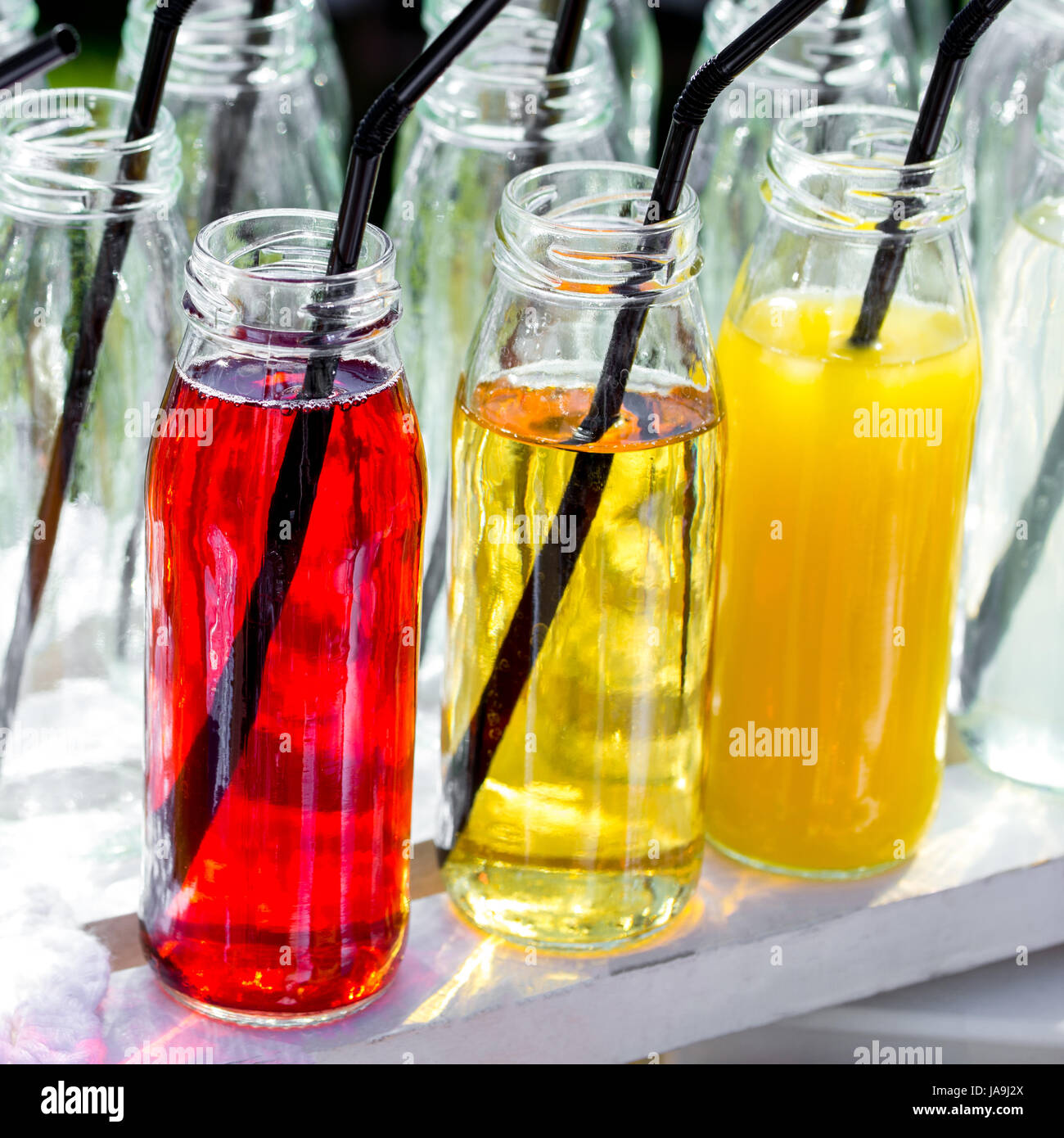 Colorful cocktails or juices, shots with straws in small glass bottles ...