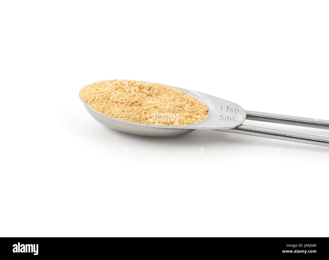 Ground ginger measured in a metal teaspoon, isolated on a white ...
