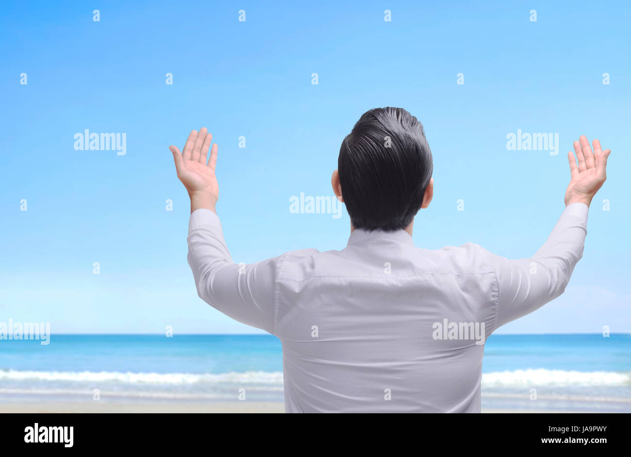Back view of asian muslim man raising hand and praying on the beach ...