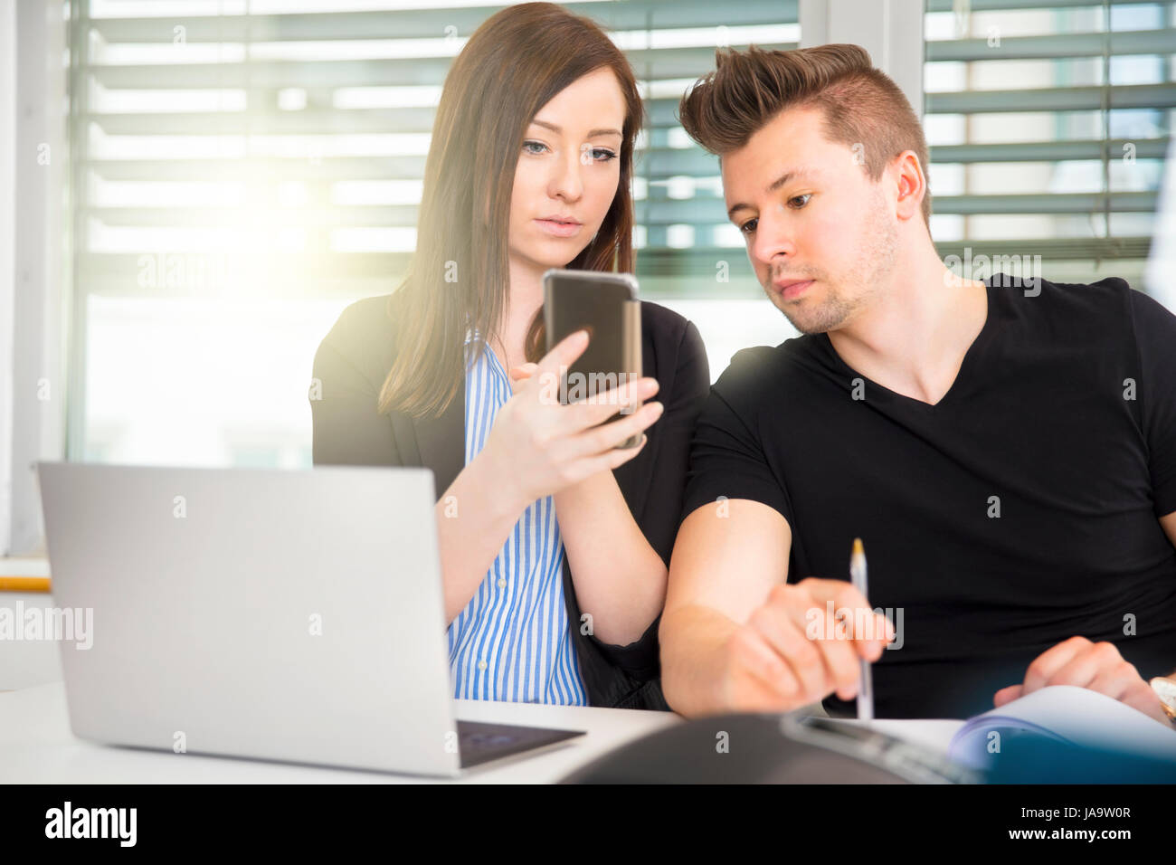 Business People Using Smart Phone At Desk In Office Stock Photo - Alamy