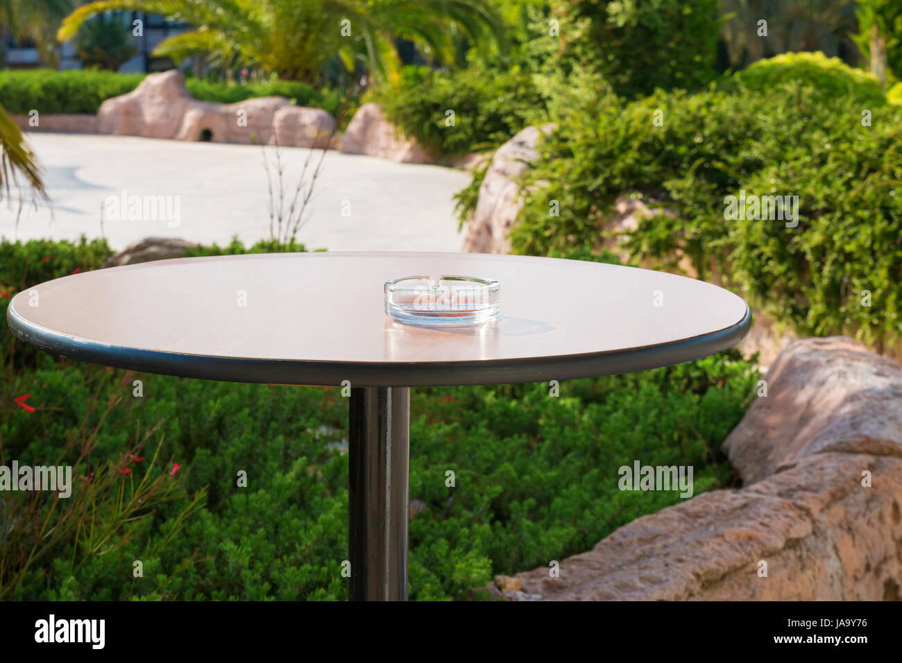 Empty ashtray on one legged, round table in the garden Stock Photo - Alamy