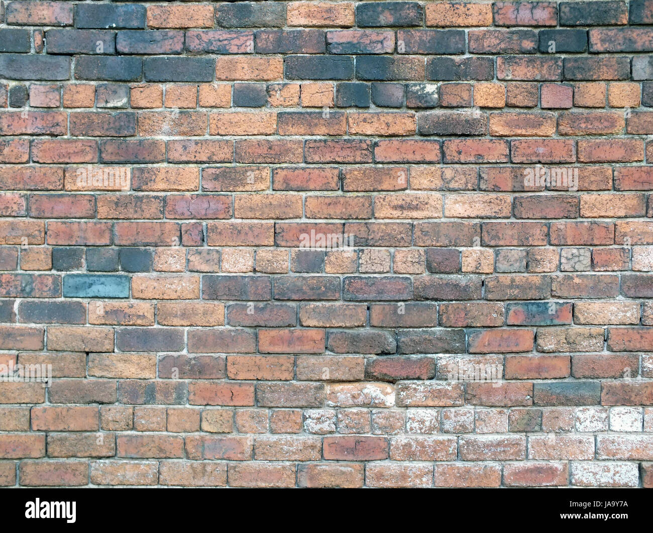 old rough red brick wall with blackened bricks and repair Stock Photo ...
