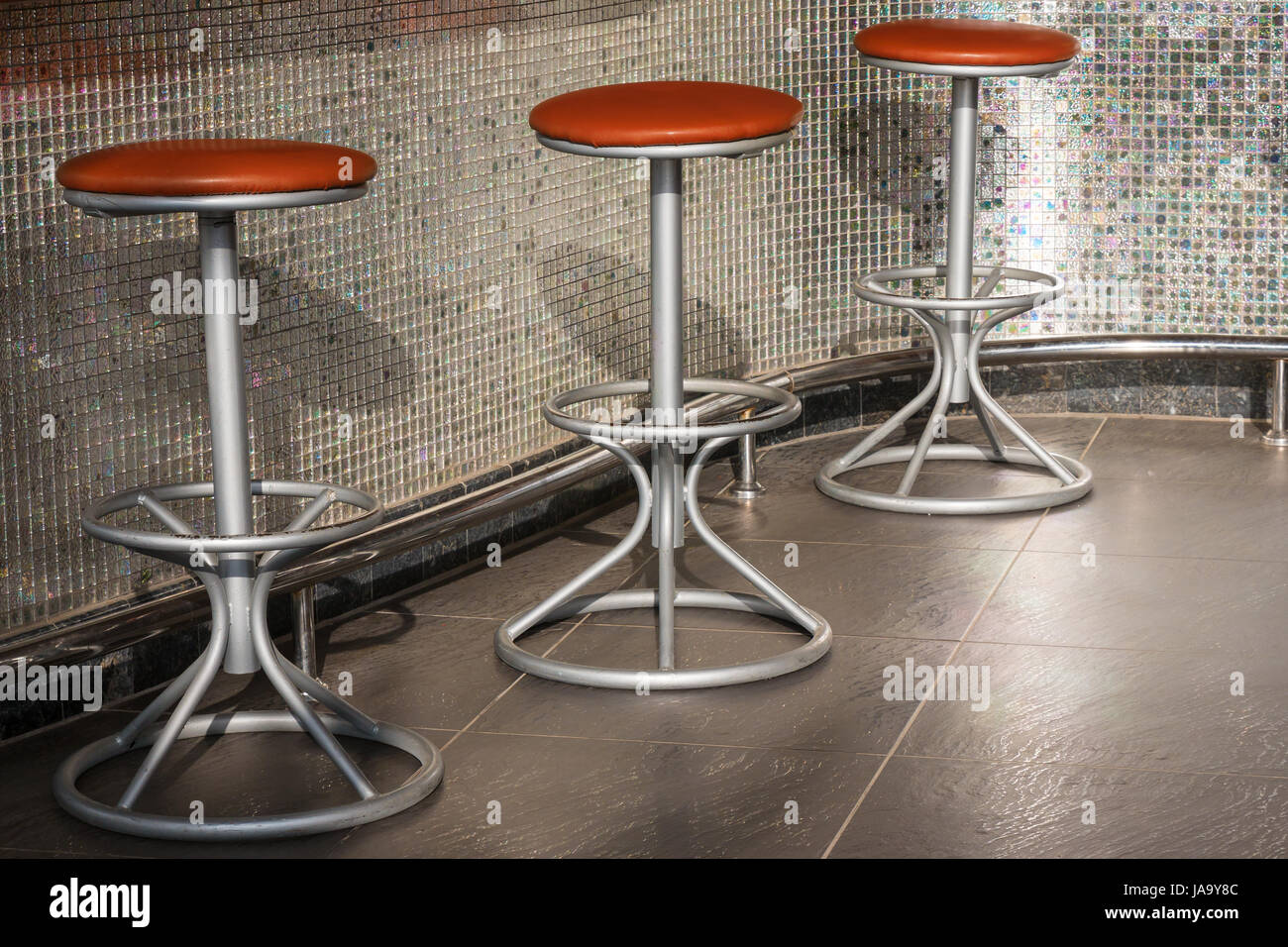 Bar stools in front of colorful mosaic wall Stock Photo - Alamy