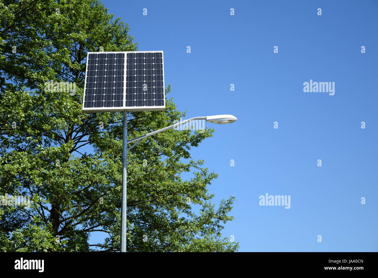 Modern street lamp with solar panel against the background of green ...