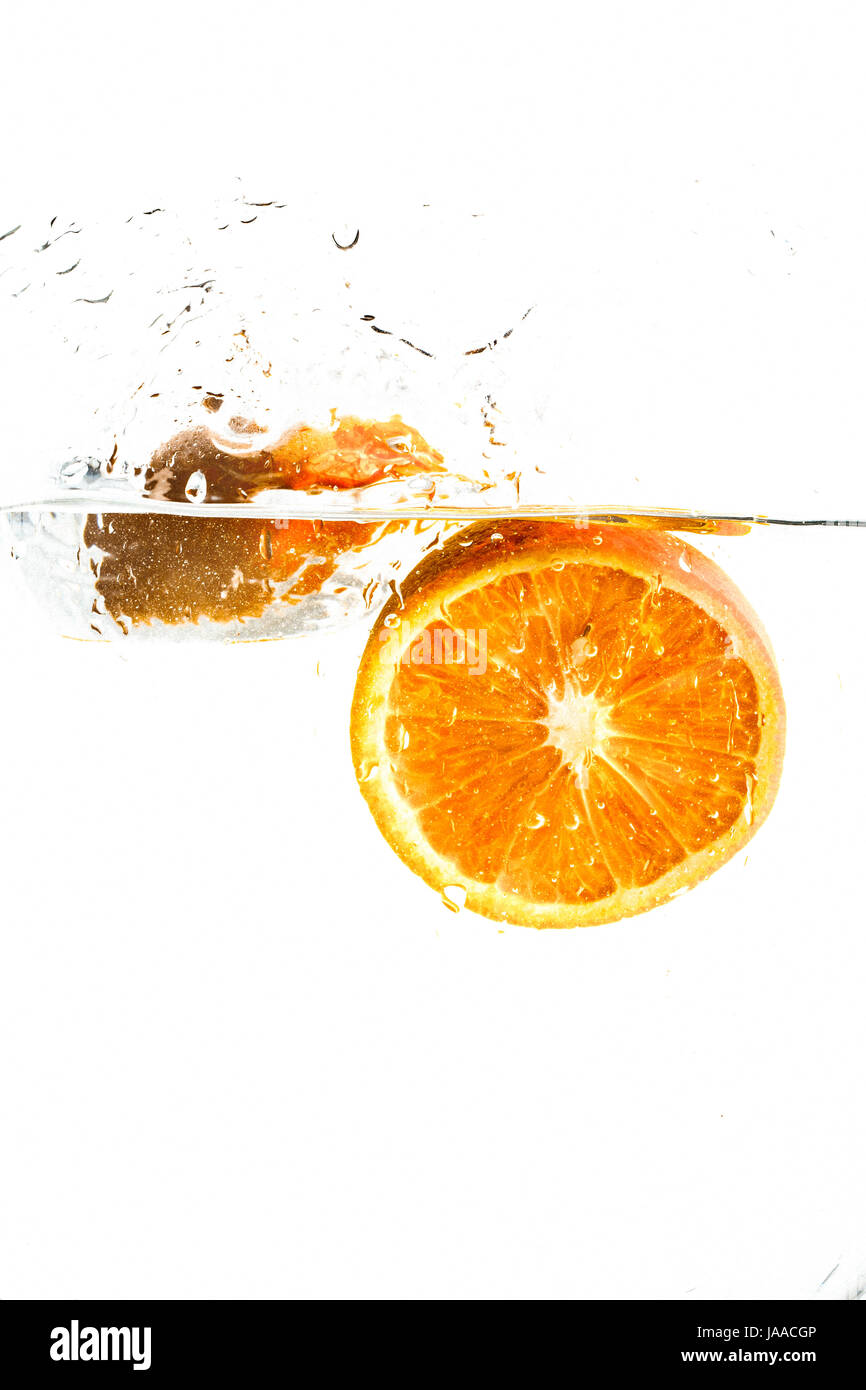 orange halves falling into water on white background Stock Photo - Alamy