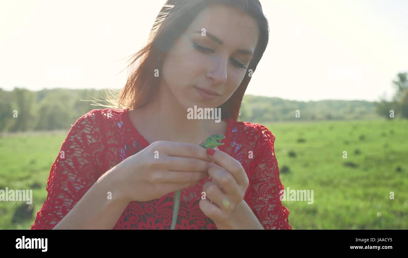 The girl is holding lizard. Girl in nature holds a green lizard ...