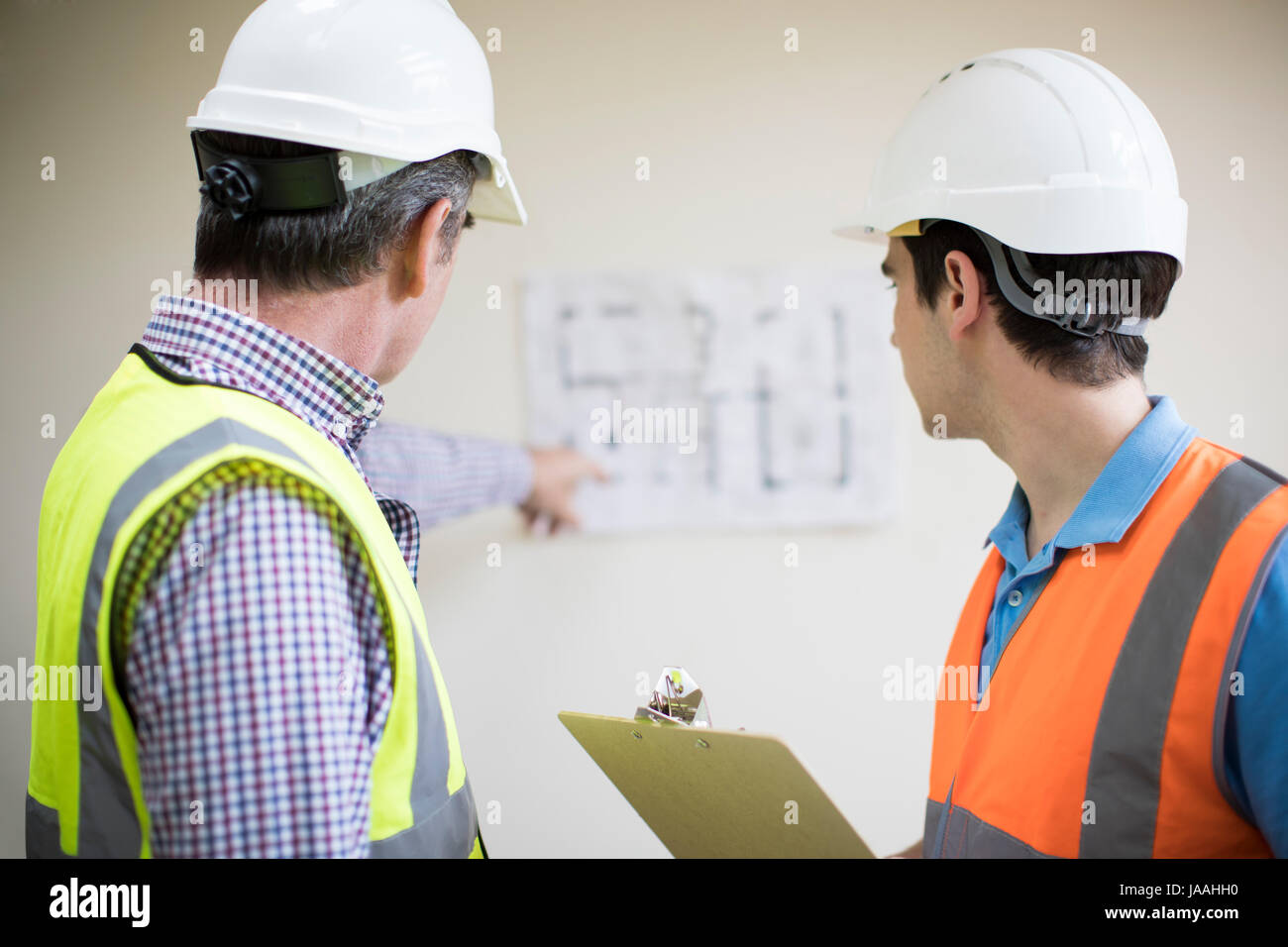 Rear View Of Architect On Site Discussing Plans With Builder Stock ...