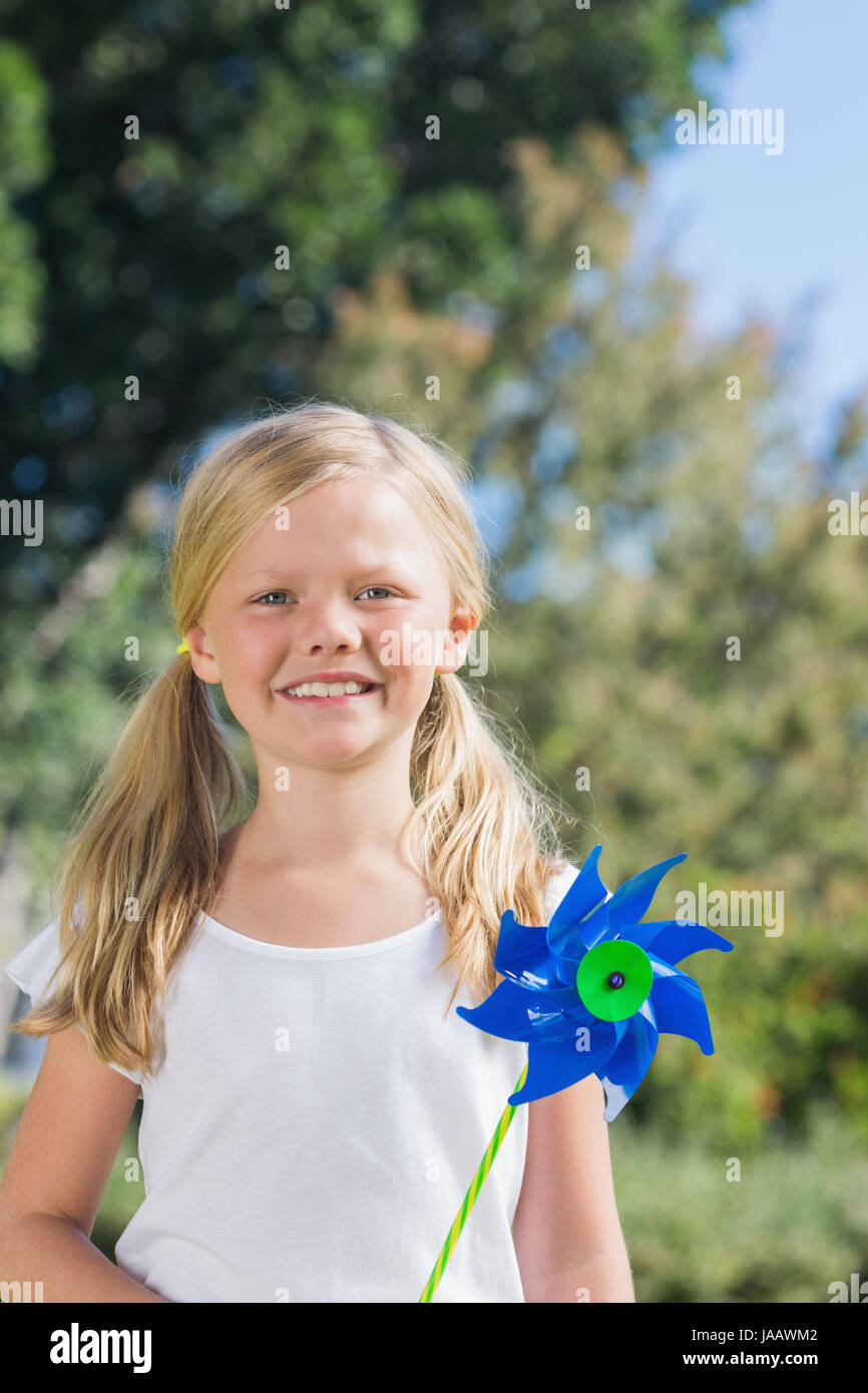 Cute Blonde Girl Holding Pinwheel Smiling At Camera In The Park In