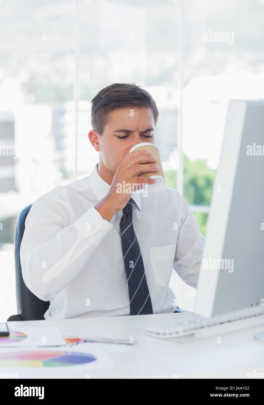 Young businessman drinking coffee at his desk at work Stock Photo - Alamy