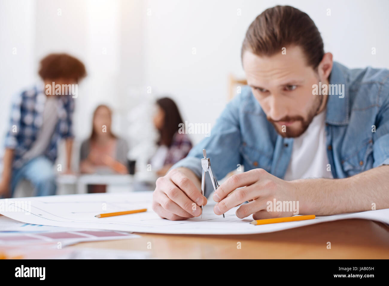 Completing drawing. Young responsible inventive man sitting in class ...