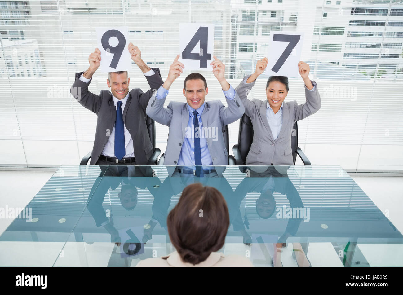 Smiling interview panel in bright office holding signs above their head ...