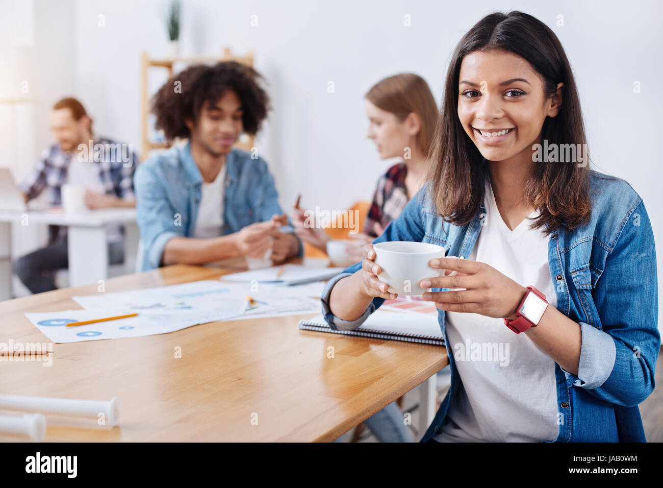 Surrounded by friends. Cute charming intelligent woman drinking some ...