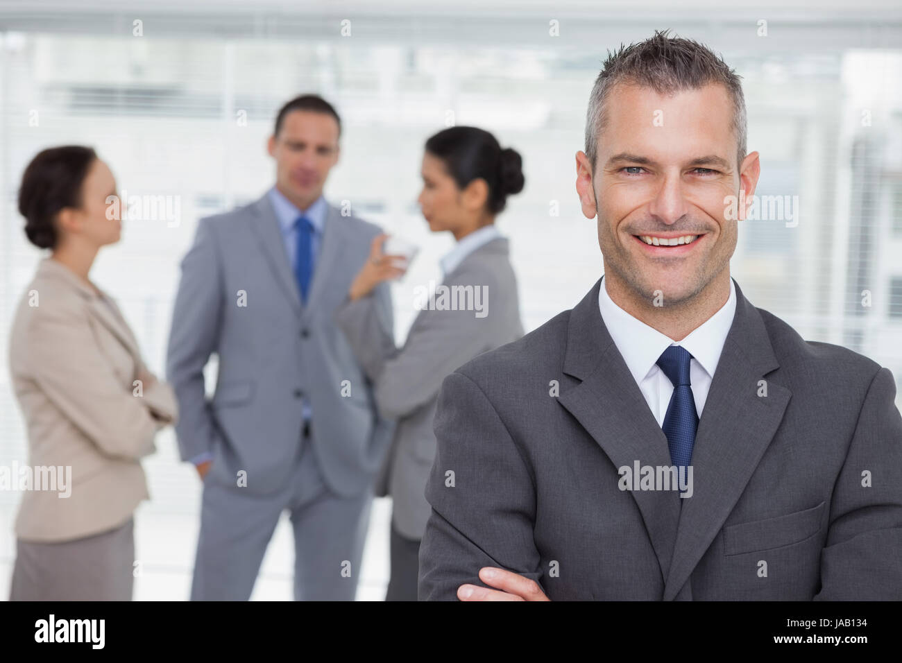 Smiling manager posing with employees in background in bright office ...