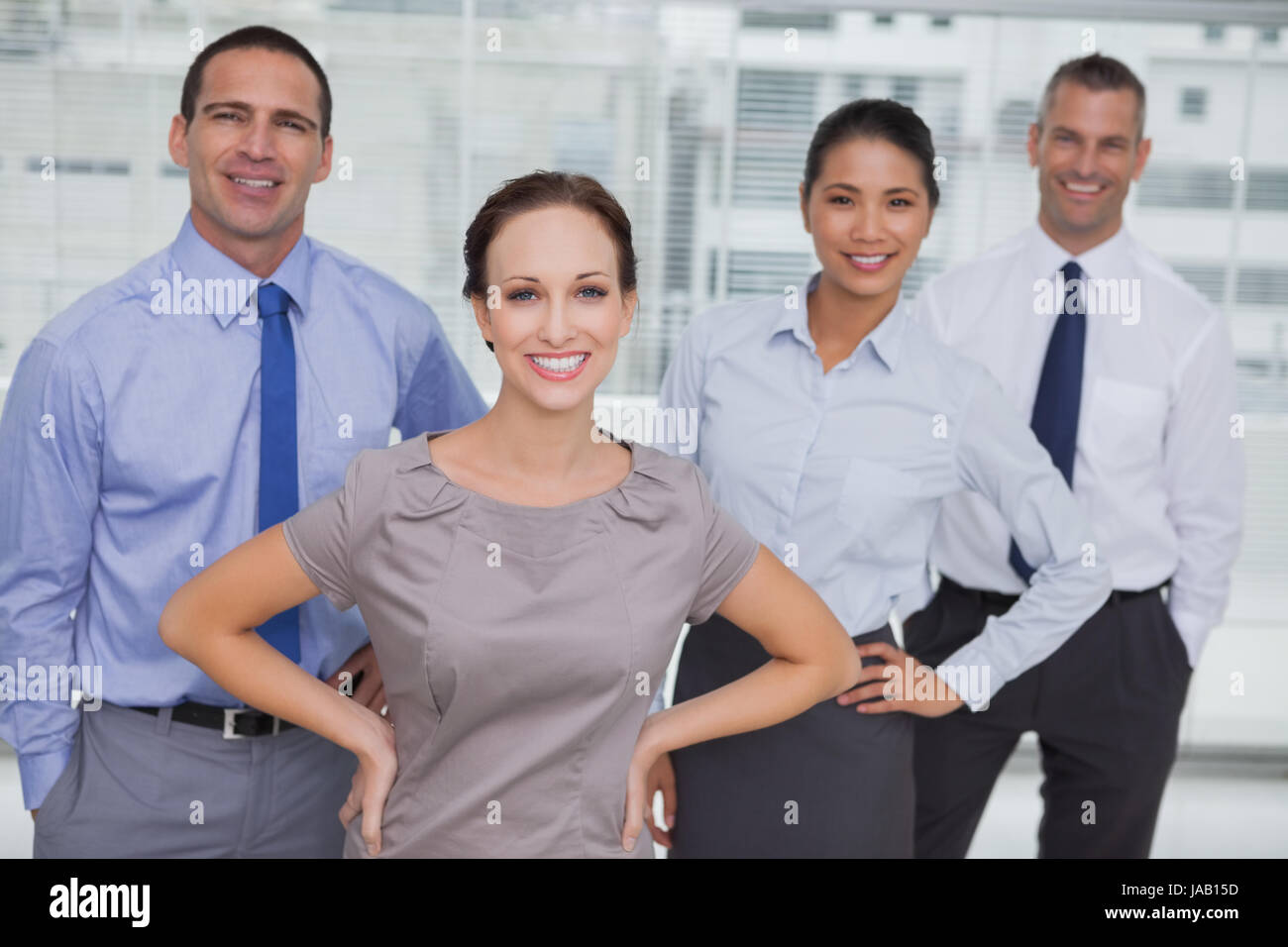 Smiling work team posing together looking at camera in bright office ...