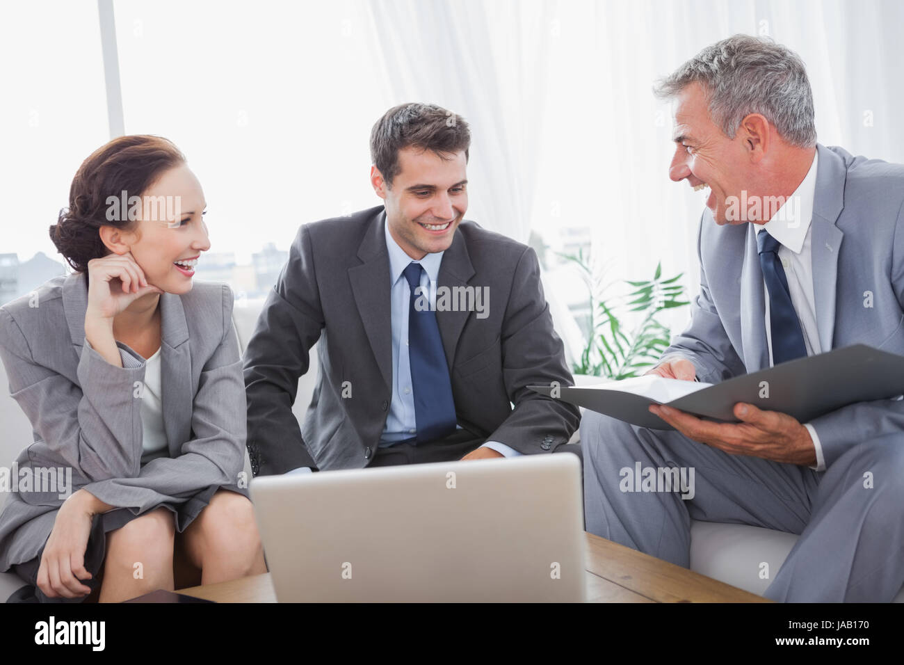 Business people laughing while having a meeting in cosy meeting room ...