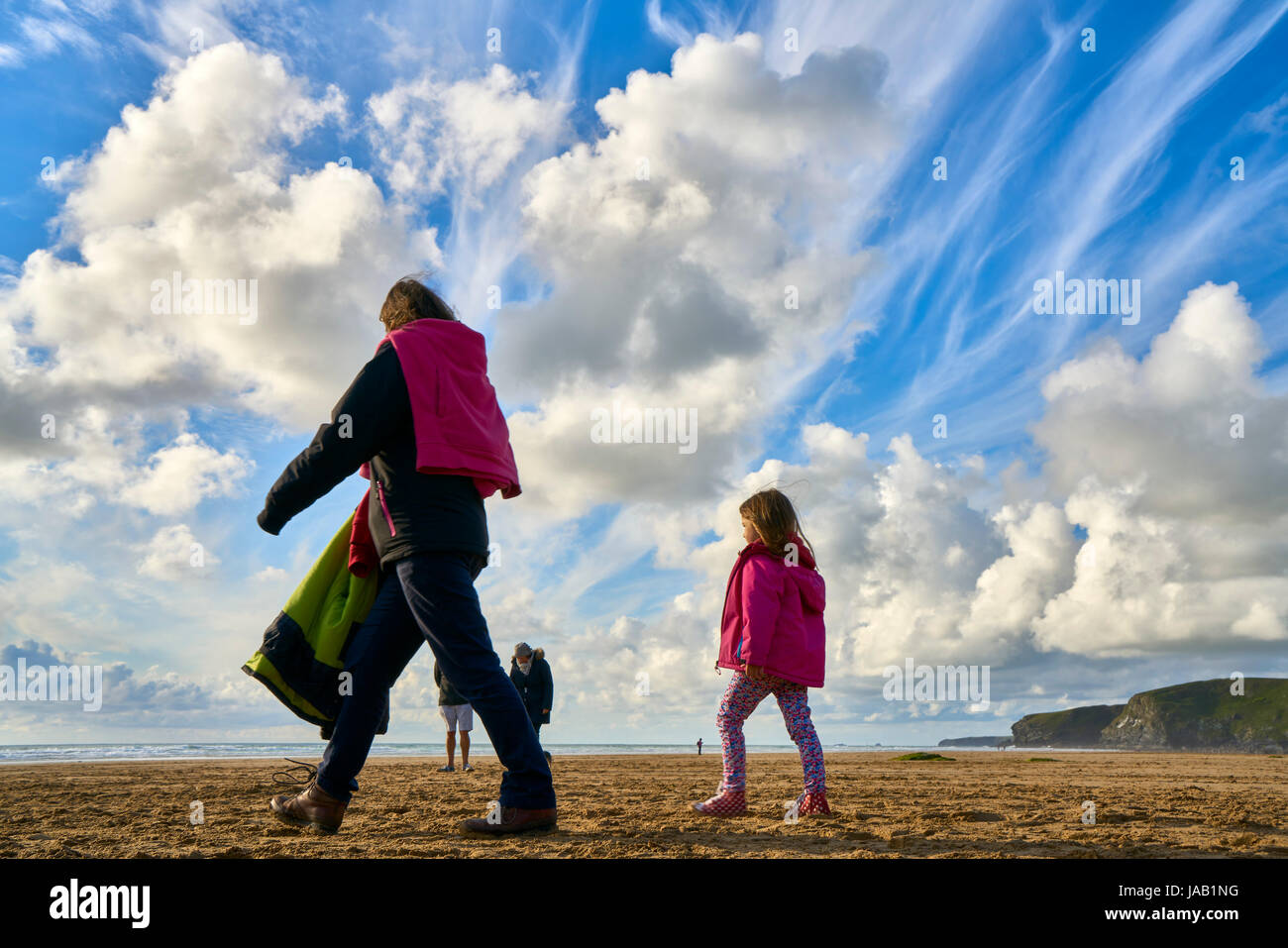 People walking on the beach underneath a big blue sky with high white ...