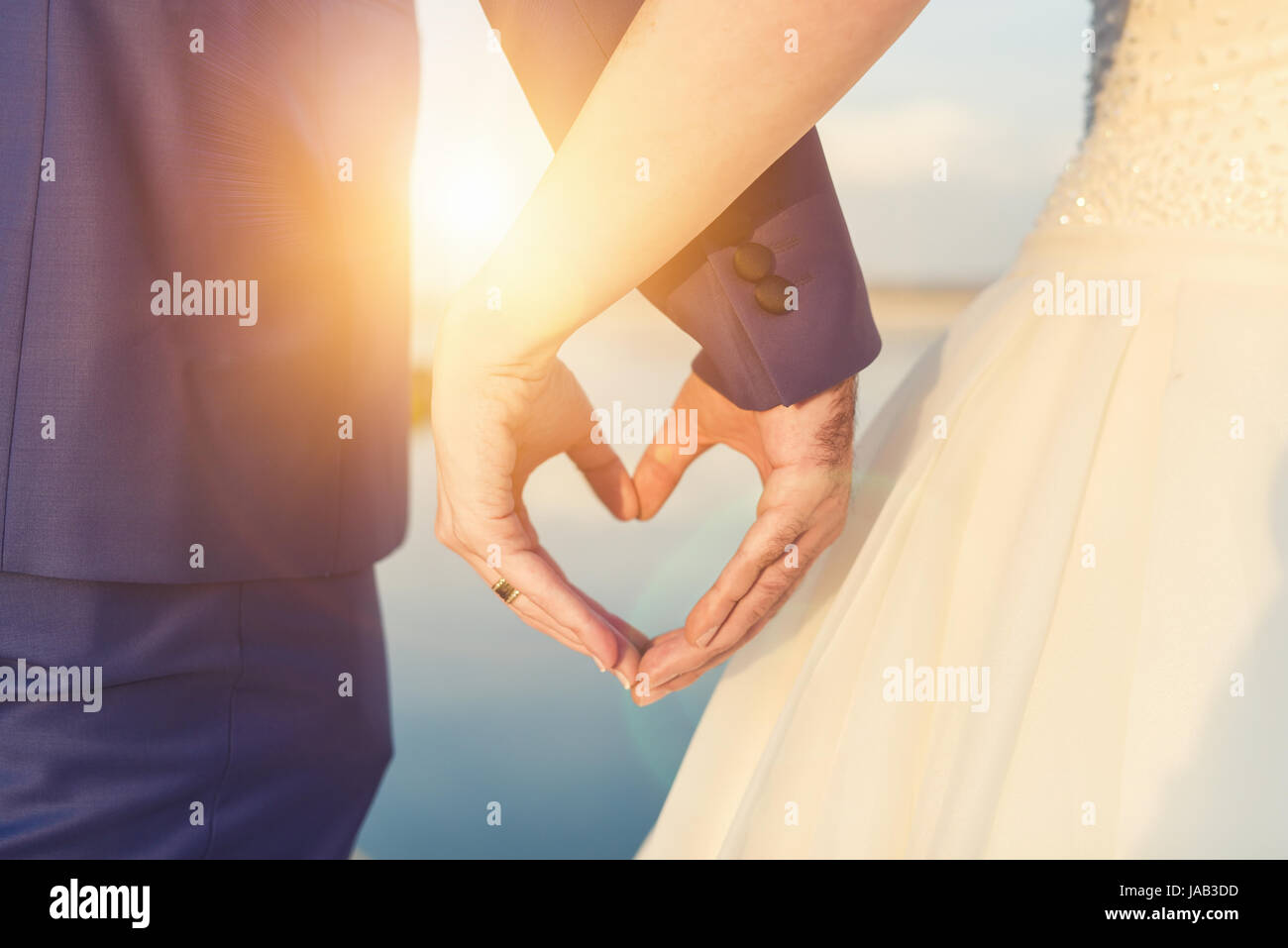 Wedding couple holding hands on sunset background Stock Photo - Alamy