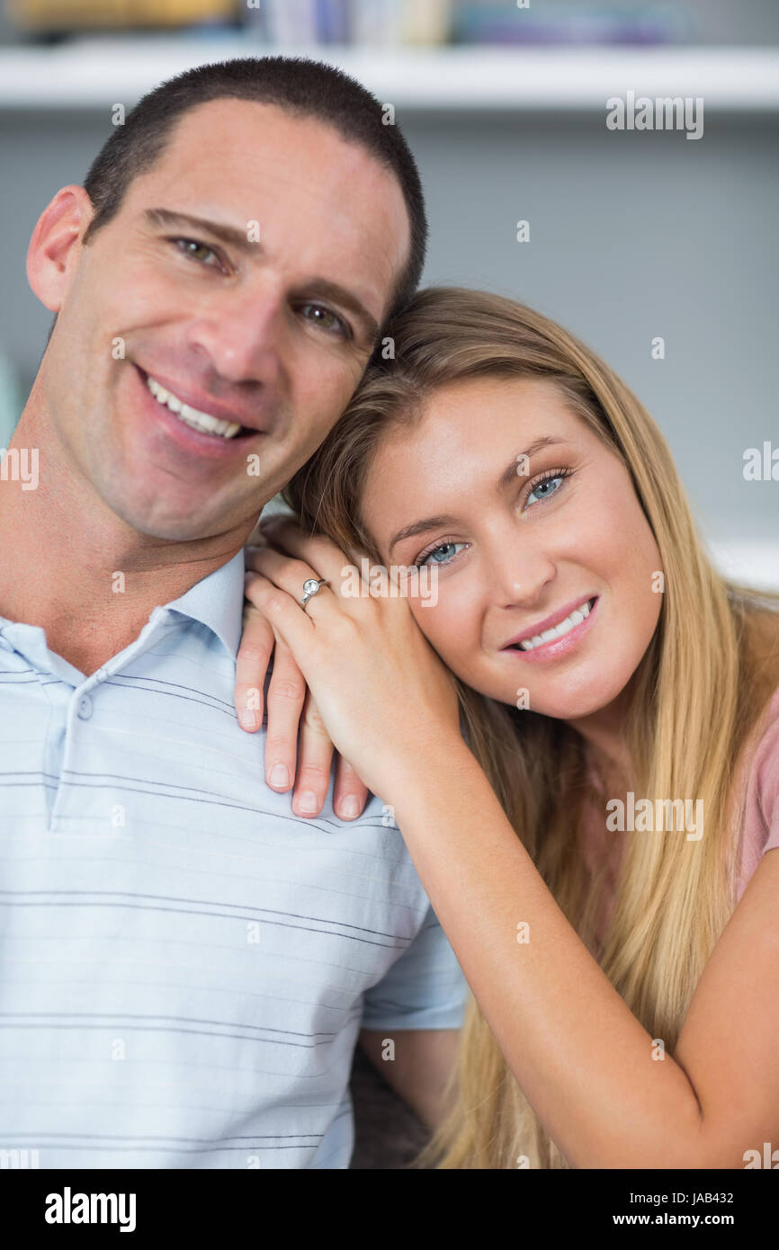 Cute couple sitting on the couch smiling at camera in sitting room at ...