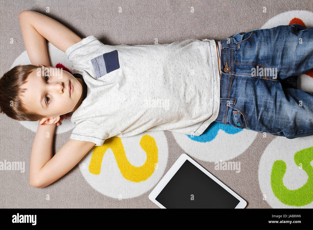 Kid with tablet computer lying on the floor at home. Top view Stock ...