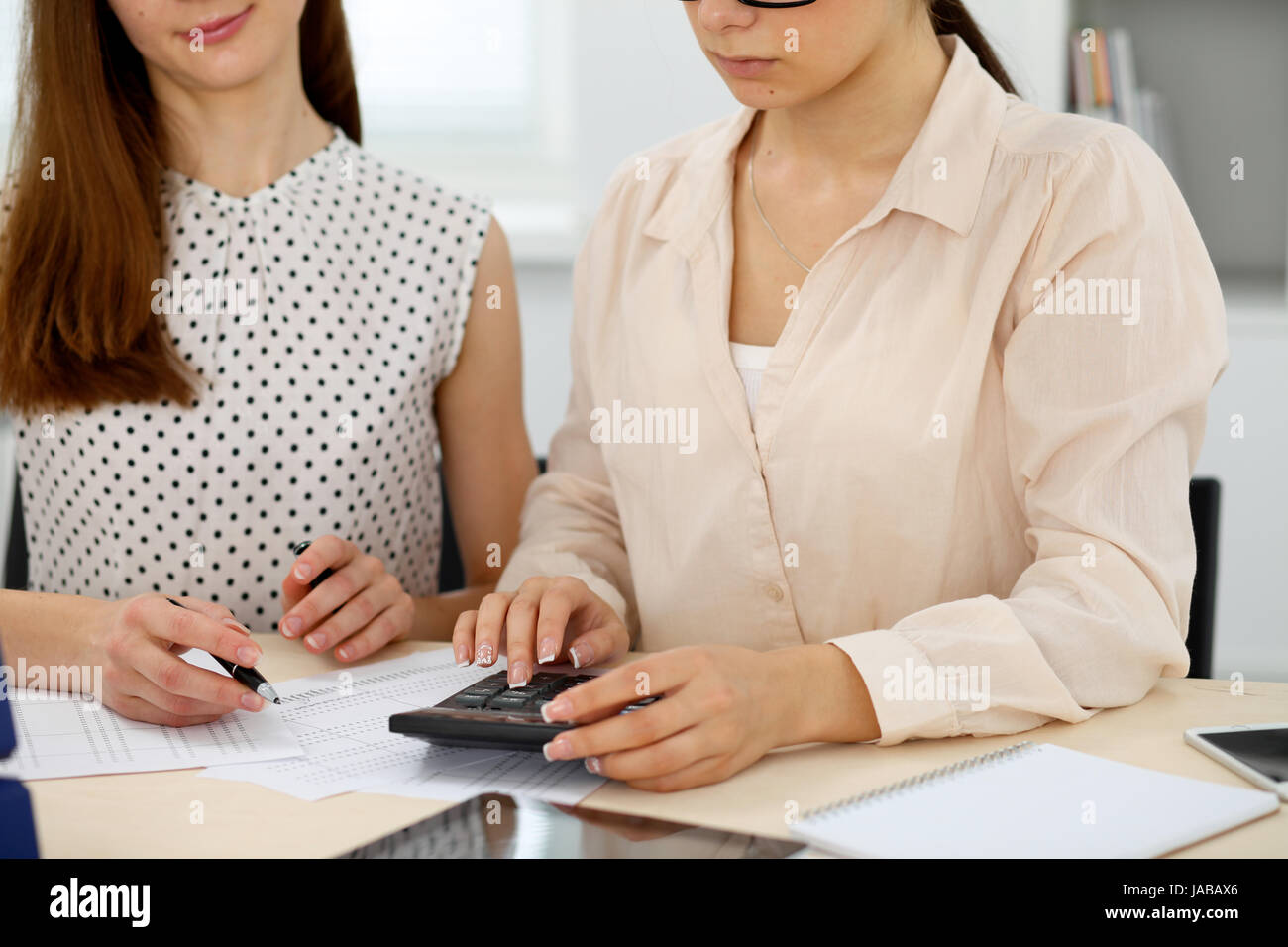 Two female accountants counting on calculator income for tax form ...