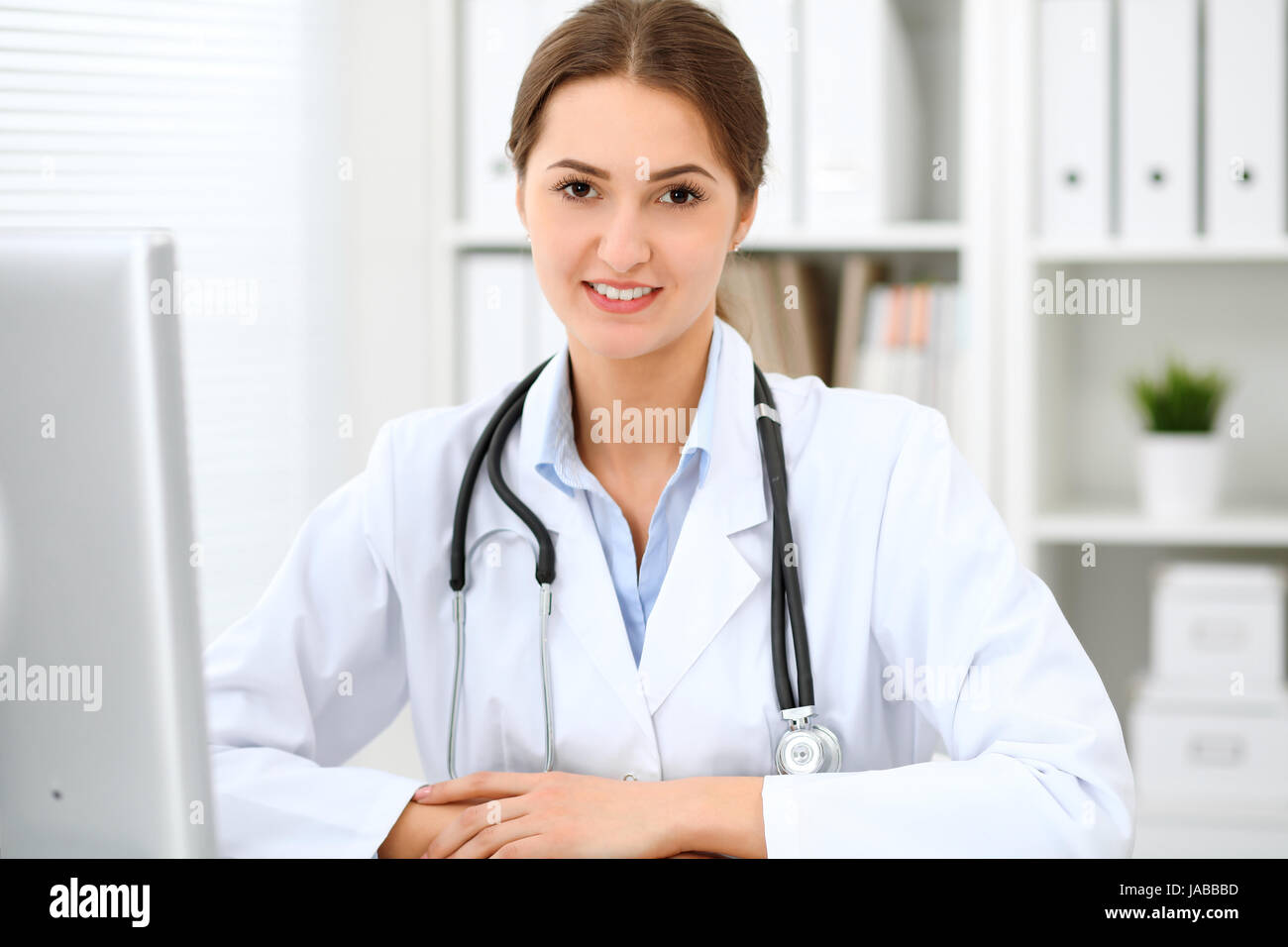 Young Brunette Female Doctor Sitting At The Table And Working At