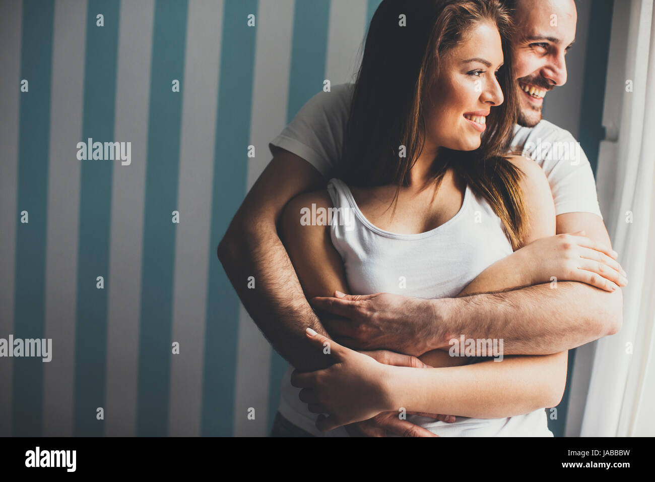 Young Guy Embracing His Girlfriend And Both Looking Through Window