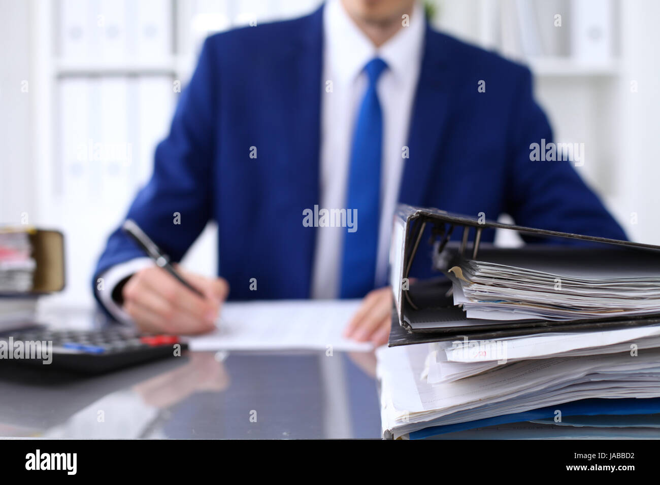 Binders with papers are waiting to be processed with businessman back ...