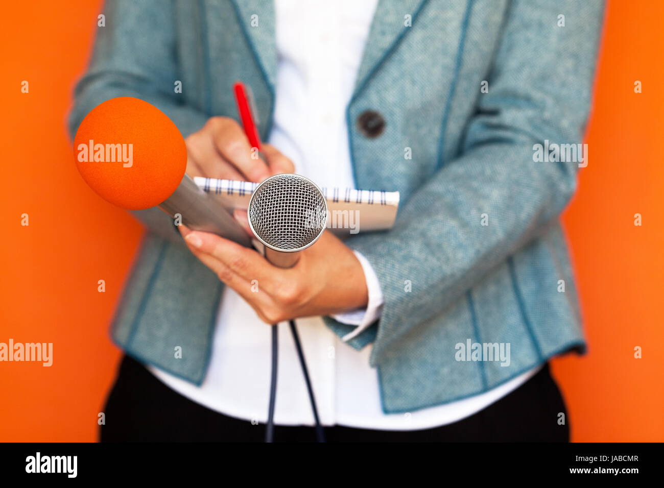 Female reporter at news conference, writing notes, holding microphones ...