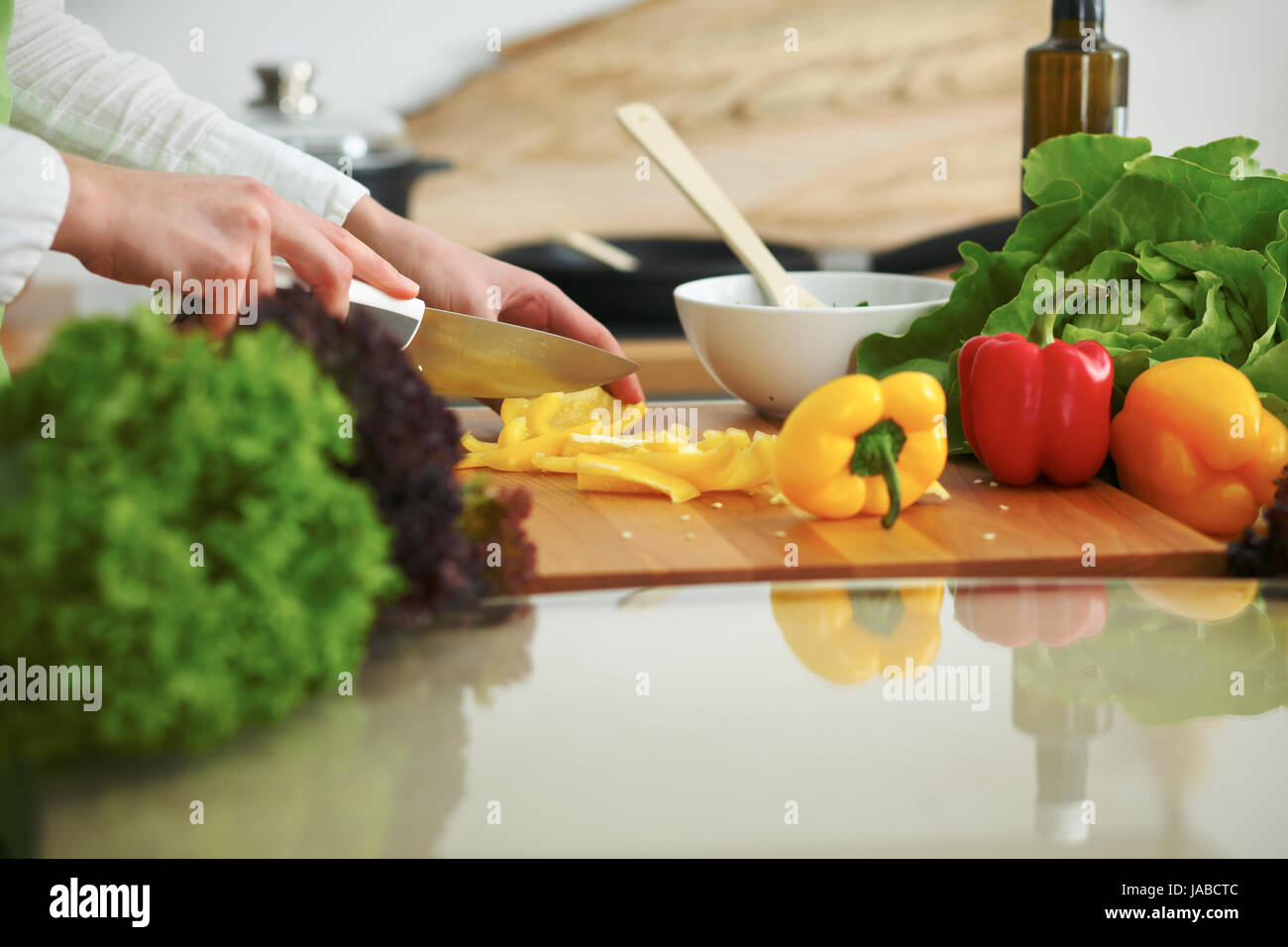 Closeup of human hands cooking vegetables salad in kitchen on the glass ...