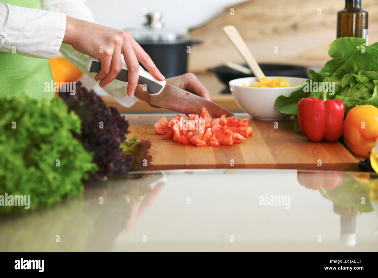 Closeup of human hands cooking vegetables salad in kitchen on the glass ...